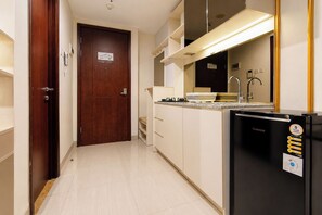 Cozinha compacta com geladeira preta, pia e porta de madeira.