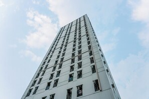 Um edifício alto e moderno, com uma fachada em grade de janelas e varandas.