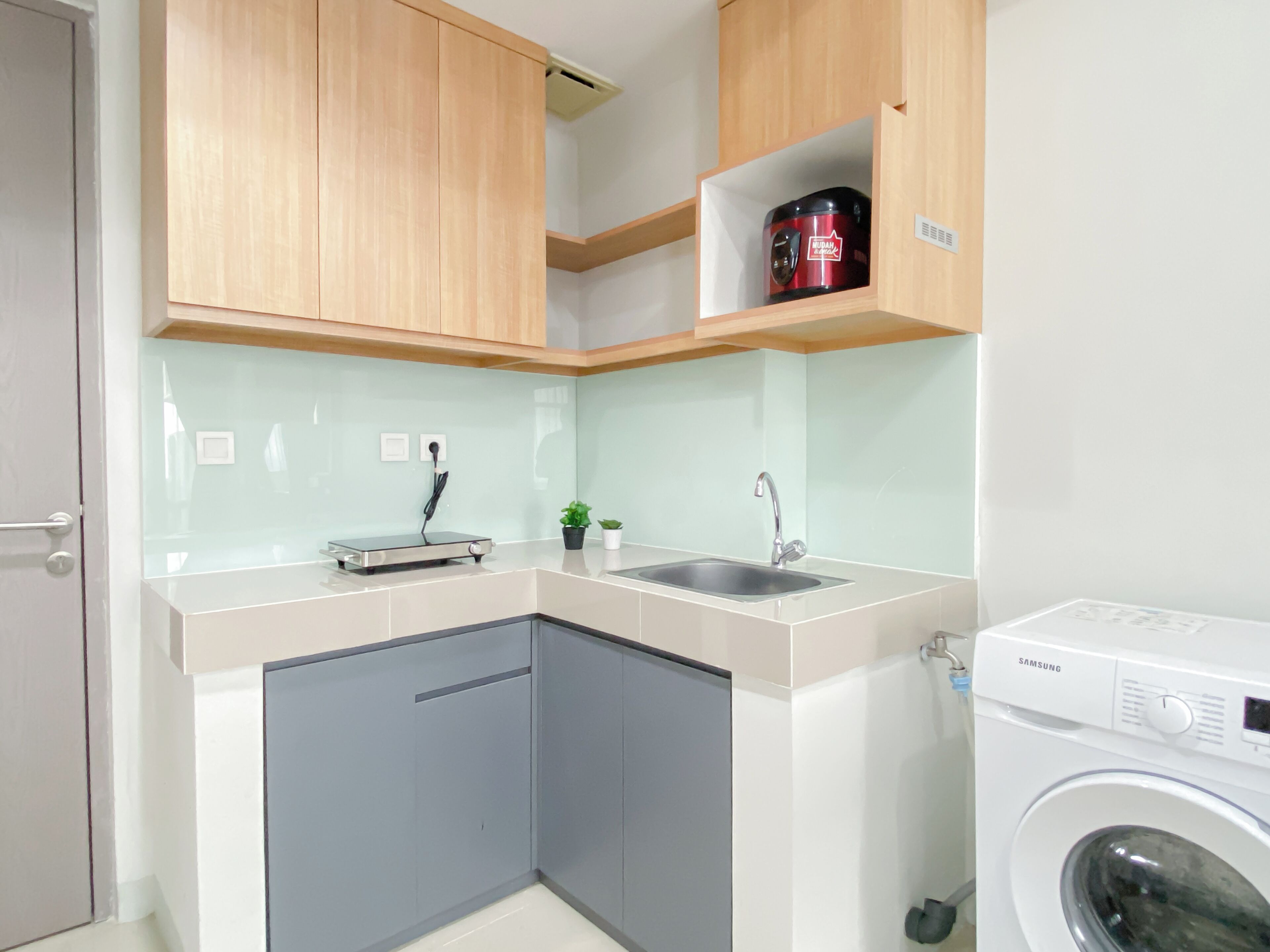 Cozinha compacta equipada com lava-louças, máquina de lavar roupa e uma bancada pequena com pia.