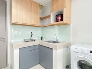 Cozinha compacta equipada com lava-louças, máquina de lavar roupa e uma bancada pequena com pia.