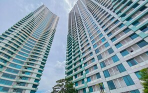 Dois edifícios altos com design arquitetônico moderno, apresentando uma grade de janelas e varandas.