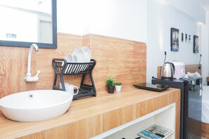 Uma casa de banho moderna com uma pia branca, um porta-toalhas preto, um espelho e uma máquina de café.