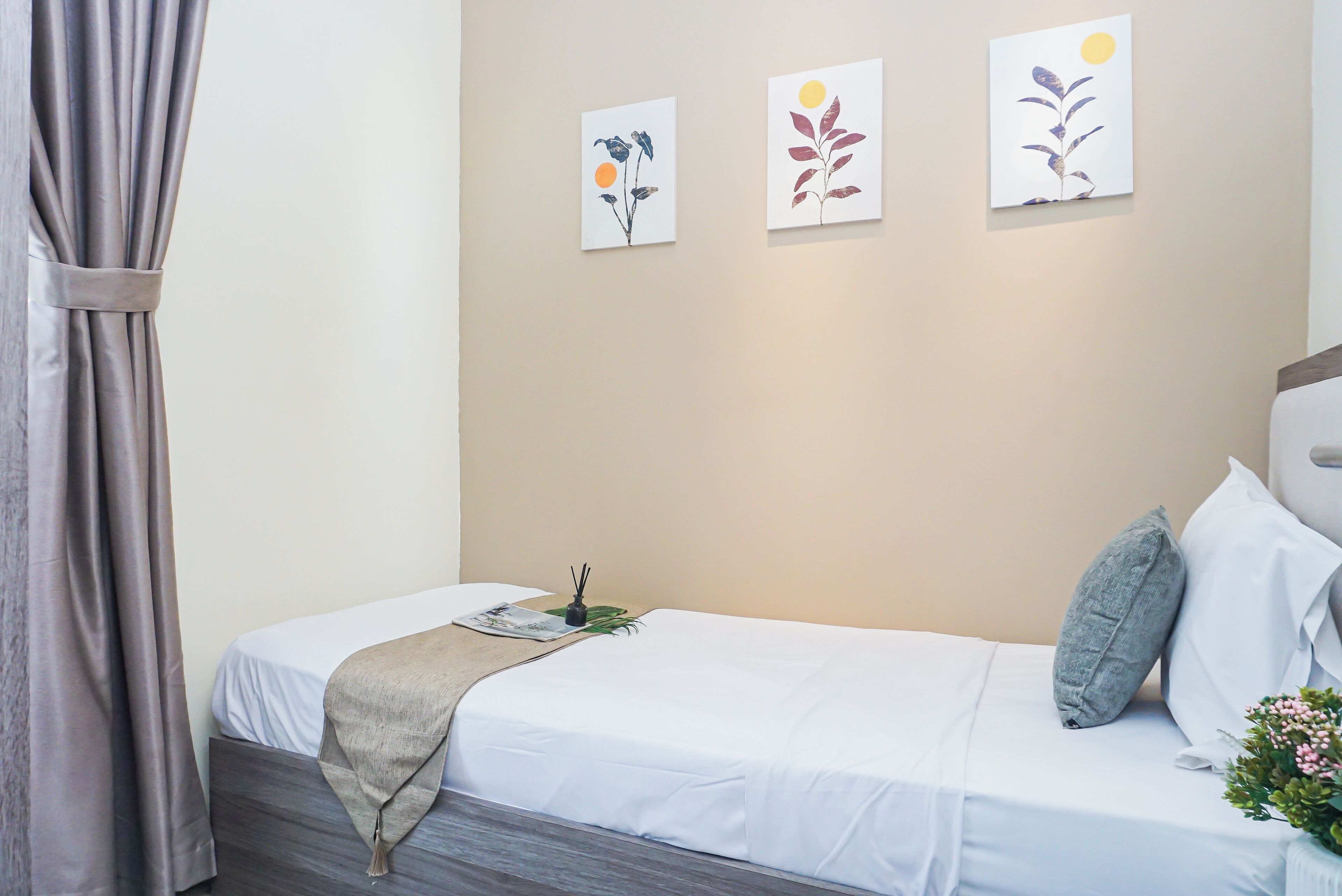 Quarto com cama, mesa de cabeceira, obra de arte na parede e cortina.