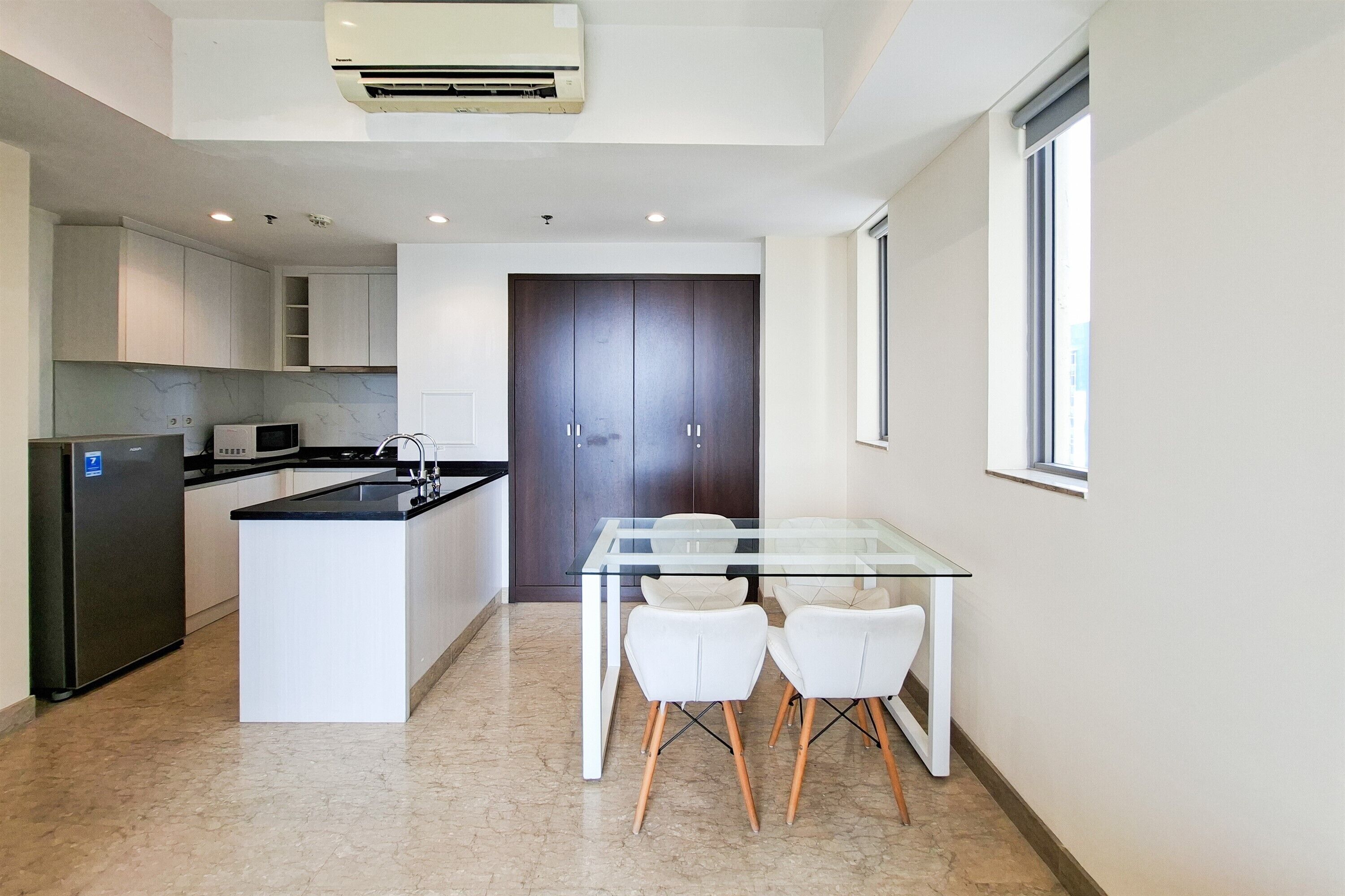Cozinha moderna com ilha central, armários brancos e porta de madeira escura.
