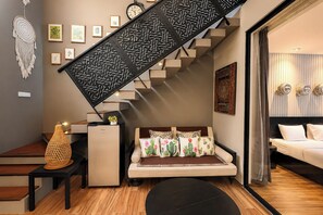 Uma sala de estar moderna com escada, um sofá com almofadas com tema de cactos, um candeeiro decorativo e obras de arte na parede.