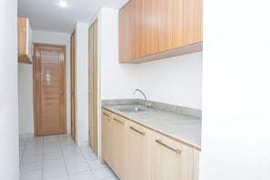 Uma cozinha compacta com pia embutida, armários de madeira e piso de azulejos.
