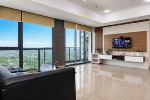Uma sala de estar moderna, com uma janela grande, televisão de tela plana e sofá de couro.