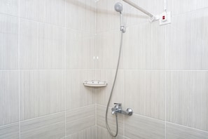 Chuveiro com chuveiro manual, painel de controle fixado na parede e mangueira para o chuveiro manual.