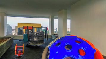 Área de recreação com escorregador, estrutura de escalada e piscina de bolinhas azul e laranja.