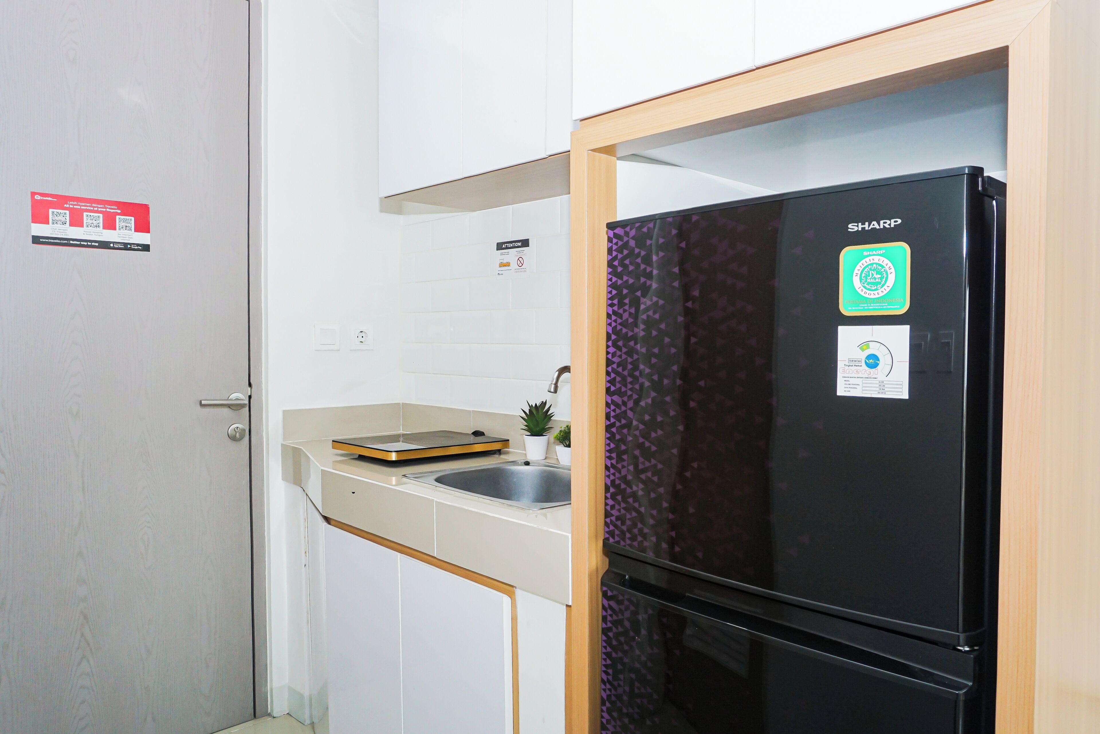 Uma cozinha compacta com geladeira preta, pia e bancada.