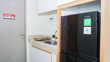 Uma cozinha compacta com geladeira preta, pia e bancada.