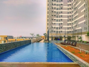 Piscina com vista para um edifício alto ao fundo.
