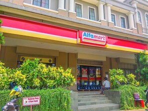 Um edifício com toldo vermelho e amarelo identificado como 'Alfamart'.
