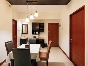 Uma sala de jantar com uma mesa, cadeiras, um micro-ondas e uma pia.