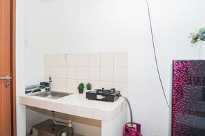 Uma cozinha compacta com pia, fogão a gás e um pequeno vaso de planta.