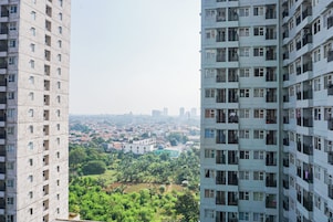 Um edifício alto com várias varandas e vista para o horizonte urbano, com edifícios residenciais e áreas verdes.