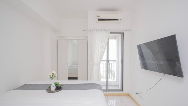 Quarto de hotel com uma cama, televisão na parede e porta de vidro corria para uma varanda.