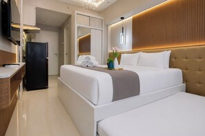Quarto de hotel moderno com cama, mesa de cabeceira e televisão integrada.