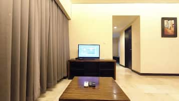 Quarto de hotel com uma mesa de madeira, um laptop em um suporte e uma televisão em um armário de madeira.