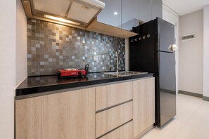 Cozinha moderna com geladeira preta, armários de madeira e painel de azulejos.