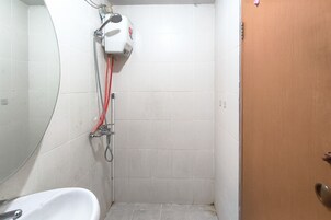 Casa de banho pequena e revestida a azulejos, com chuveiro, sanita e lavatório.