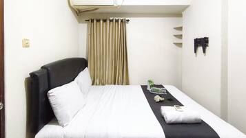 Quarto de hotel com cama, mesa de cabeceira, controle remoto e janela com cortinas.
