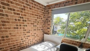 Um quarto pequeno com uma cama, uma escrivaninha e uma janela.