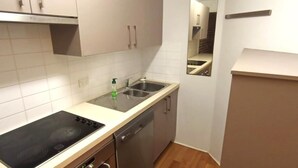 Uma cozinha compacta com fogão, lava-louças e duas pias.