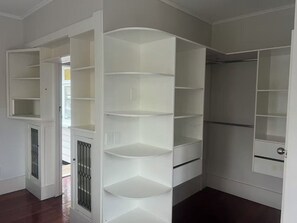 Quarto com estantes embutidas e porta com grades de metal.