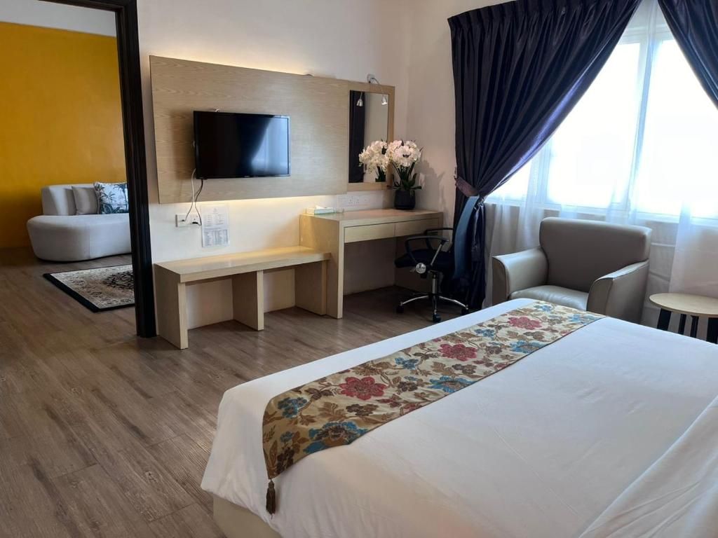 Quarto de hotel com cama, escrivaninha, cadeira, televisão e janela com cortinas.
