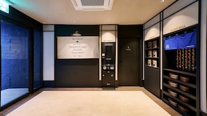 Uma área de recepção de hotel com um quiosque de check-in automático, um balcão de atendimento e uma exposição de tigelas de madeira.