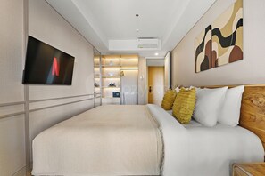 Quarto de hotel com uma cama, televisão na parede e um quadro sobre a cama.