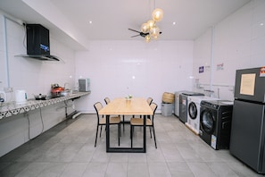 Cozinha moderna com mesa de jantar, cadeiras, forno embutido, máquina de lavar roupa e ventoinha no teto.