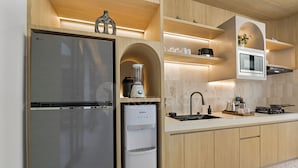 Cozinha moderna com eletrodomésticos de aço inoxidável, armários de madeira e micro-ondas embutido.