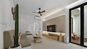 Uma sala de estar moderna com um sofá, uma mesa de centro, uma televisão e um cacto.