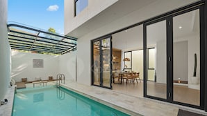 Piscina moderna ao ar livre com cobertura de vidro, área de estar no terraço e vista para a sala de estar adjacente.