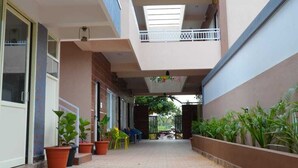 Um edifício com uma placa indicando ser uma residência para hóspedes. Há plantas em vasos ao longo da passarela.