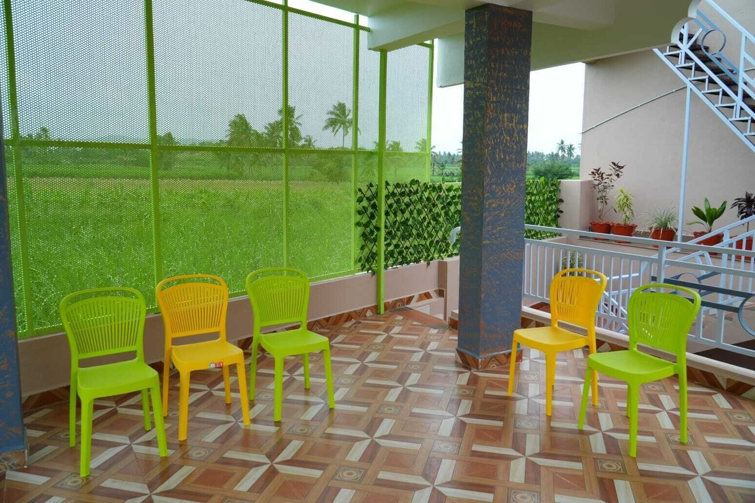 Uma área de estar coberta ao ar livre, com cadeiras e piso estampado.