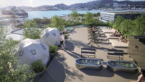 Um terraço no terraço com piscina, áreas de estar e vista para a cidade e para a água.