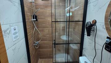 Uma casa de banho moderna com cabine de duche em vidro, sanita e bidé.