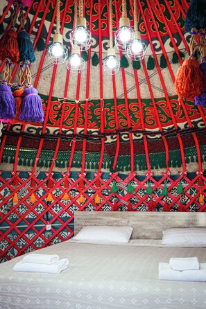 Um quarto com teto estampado, luminárias pendentes e uma cama com lençóis brancos.
