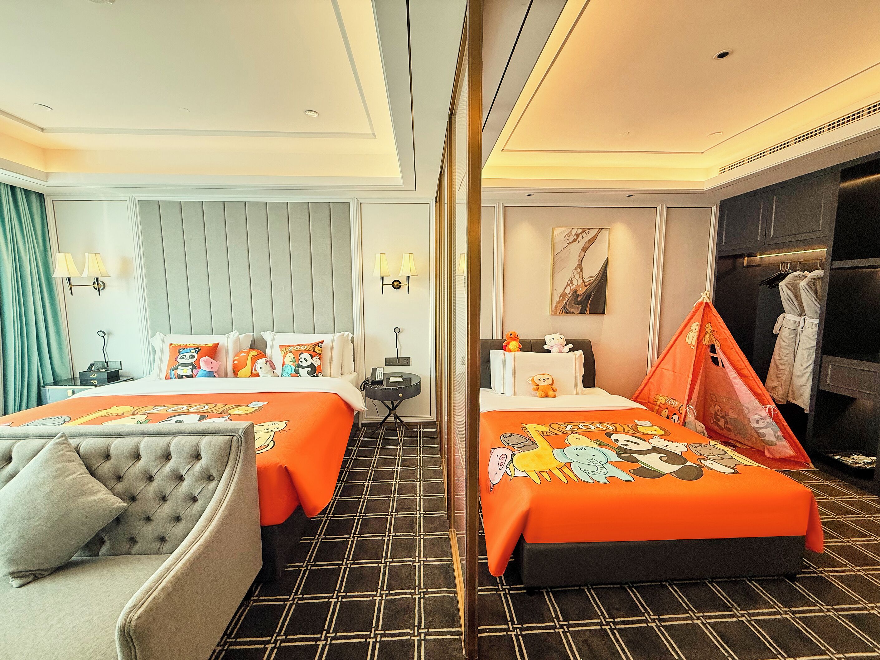 Quarto de hotel com duas camas, um sofá, um espelho, uma mesinha e um guarda-roupa.