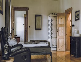 Um quarto com cama, guarda-roupa de madeira, penteadeira e espelho.