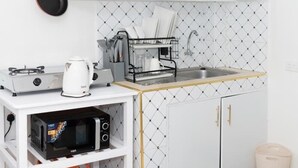 Uma cozinha compacta com armários brancos, fogão a gás, micro-ondas e pia.