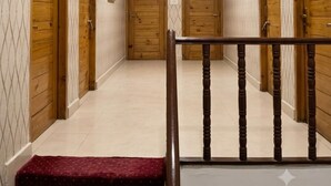 Um corredor com portas de madeira, uma escada com tapete vermelho e um corrimão de madeira.