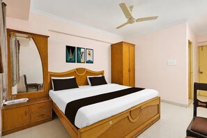 Quarto com cama de madeira, mesa de cabeceira, espelho, guarda-roupa e ventoinha no teto.