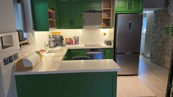 Cozinha moderna com armários verdes, eletrodomésticos de aço inoxidável e uma ilha central.