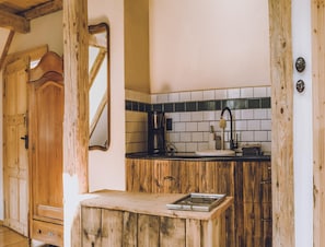 Uma cozinha rústica com armários de madeira, painel de azulejos e uma cafeteira.