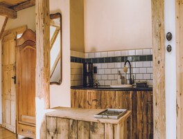 Uma cozinha rústica com armários de madeira, painel de azulejos e uma cafeteira.