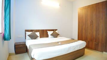Quarto com cama de madeira, mesa de cabeceira, guarda-roupa e janela com cortinas.